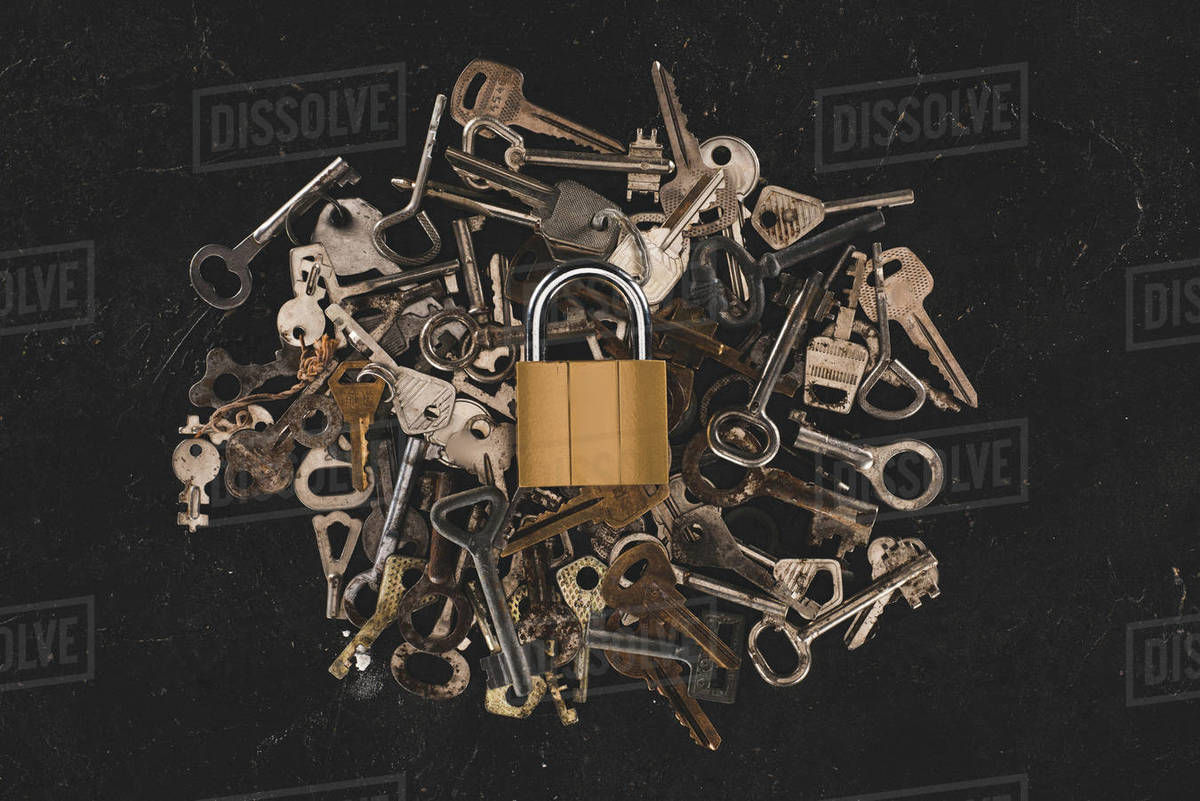 top view of heap different metal keys with lock isolated on black ...