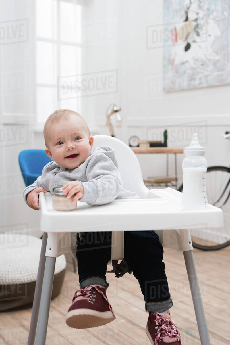 Adorable smiling child sitting in a baby chair in the kitchen - Stock ...