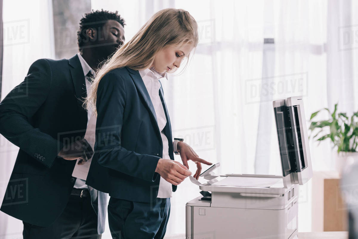 young businesspeople using copier together at office - Royalty-free ...