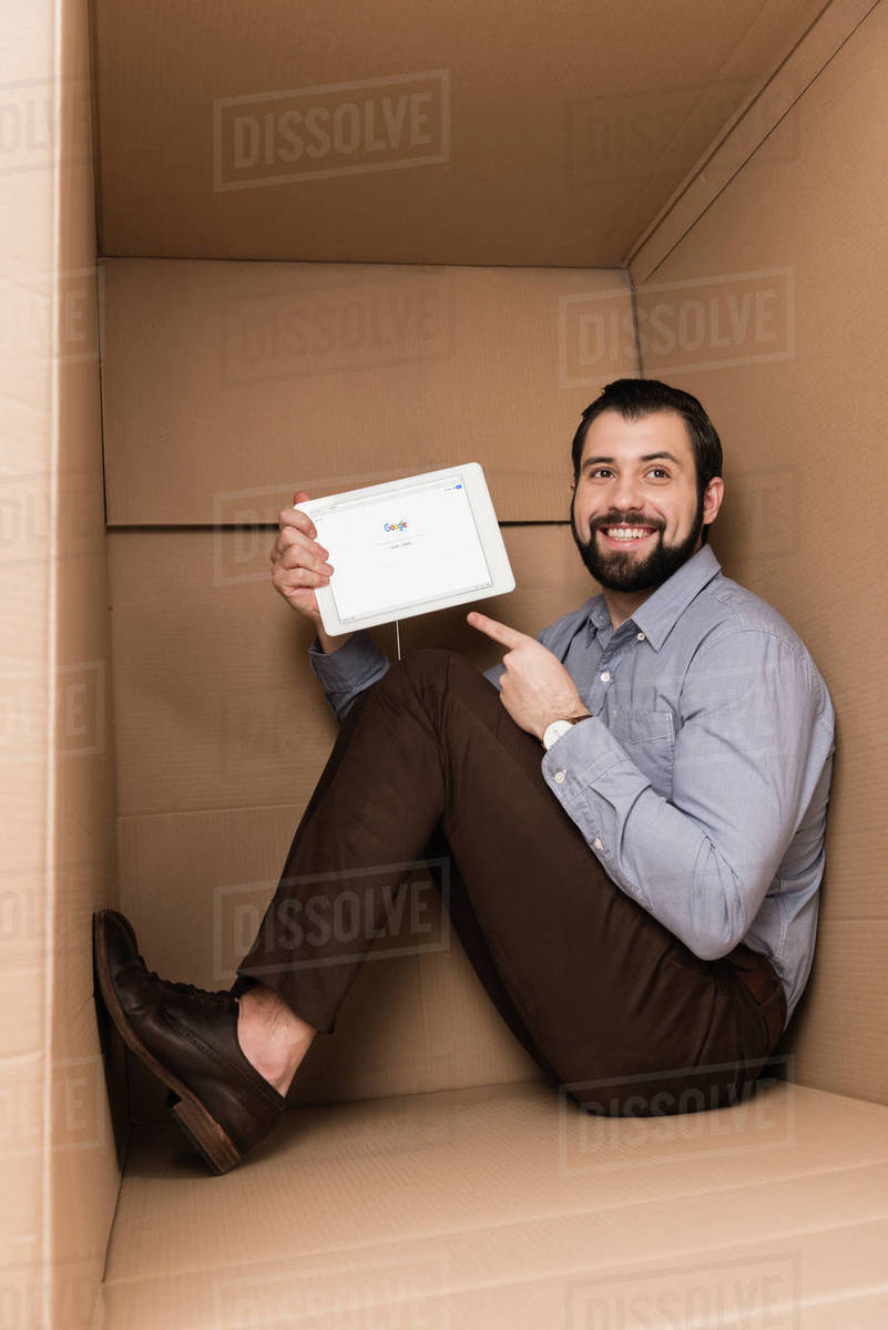 Cheerful handsome man pointing at tablet with google website while ...