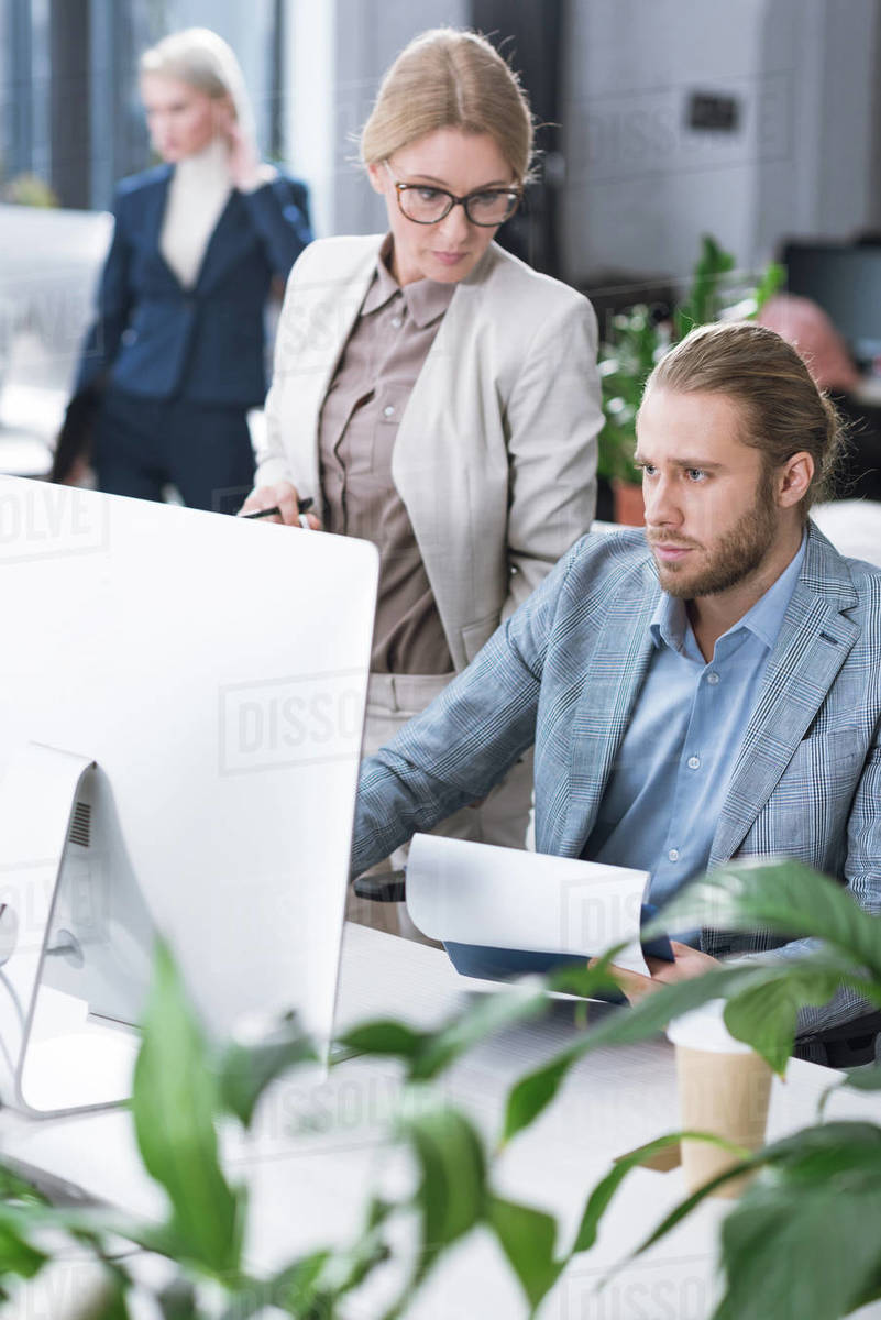 Portrait of businesswoman checking colleagues work at workplace in ...