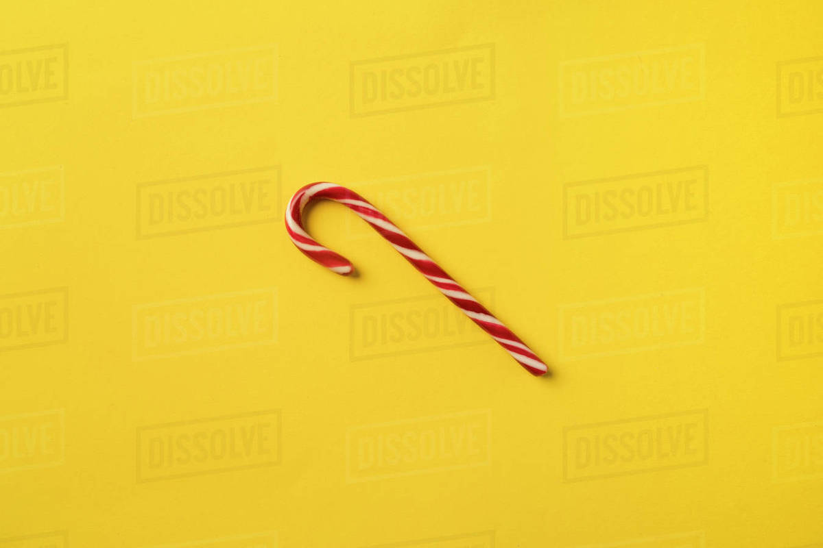 One candy cane isolated on yellow - Royalty-free Stock Photo | Dissolve