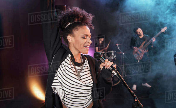 Female singer with microphone and rock and roll band performing hard ...