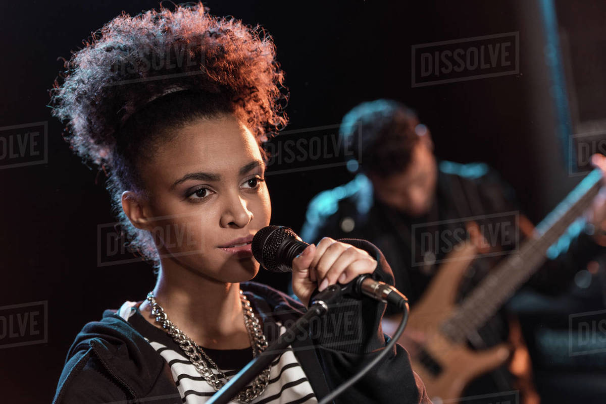 Female singer with microphone and rock and roll band performing hard ...