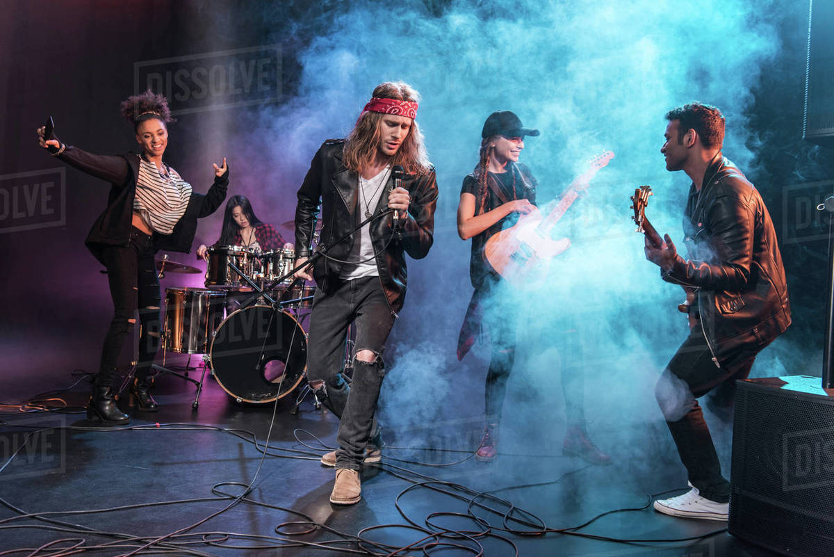 Handsome singer with rock and roll band performing music on stage ...