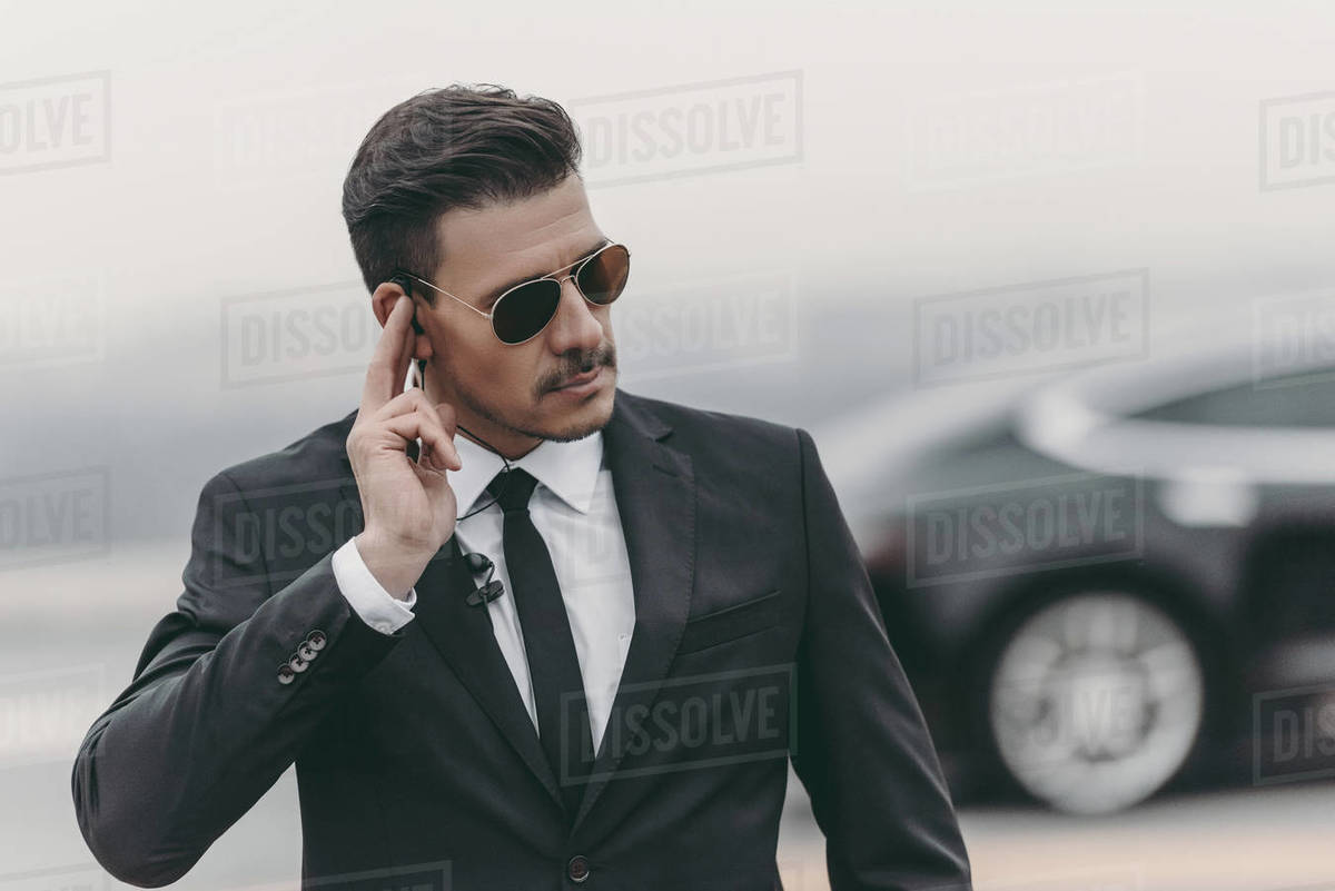 Handsome bodyguard listening message with security earpiece - Stock ...