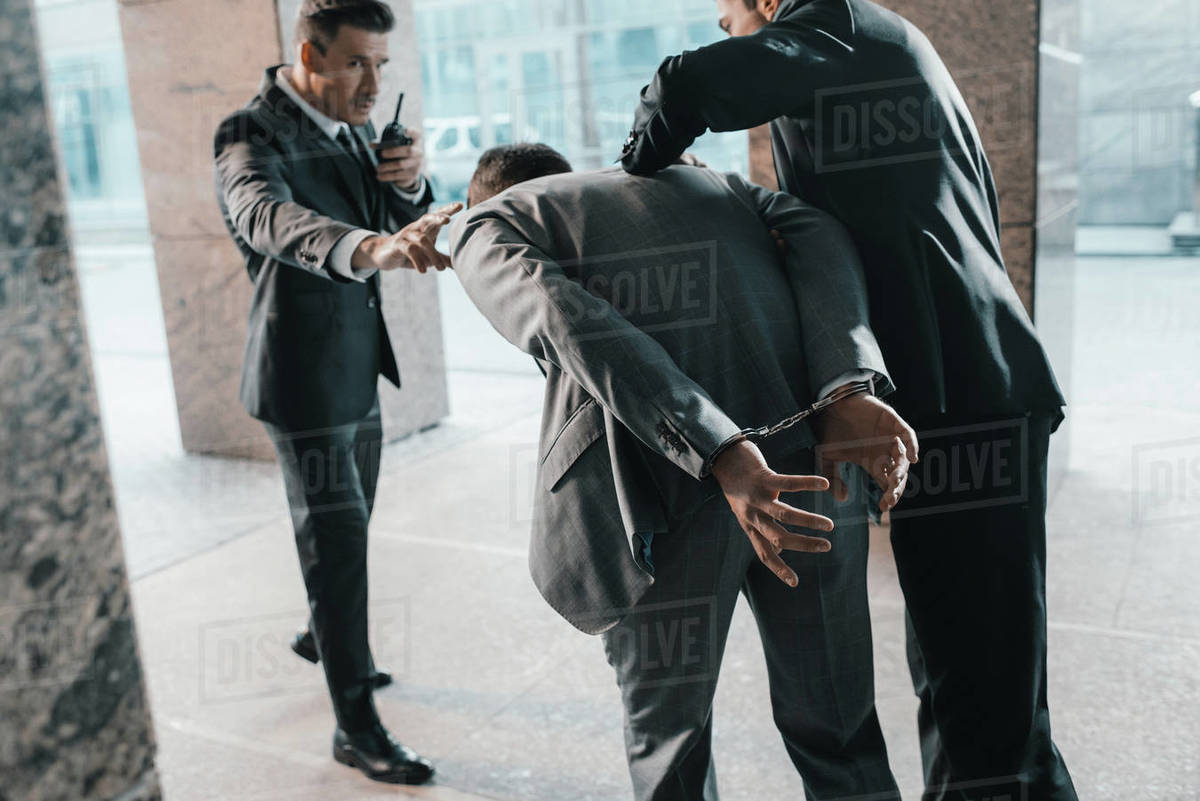 Cropped image of security guards arresting offender and talking by ...