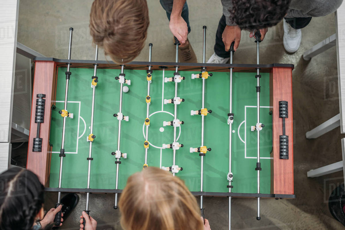 Top view of cropped multicultural people playing in table soccer at ...