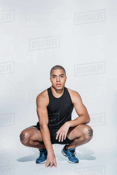 sportive african american squatting and looking at camera - Royalty ...