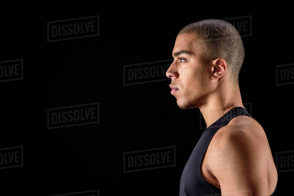 side view of serious african american man standing isolated on black ...