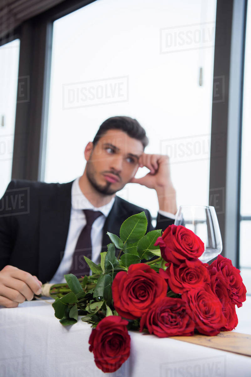 Selective focus of man in suit with bouquet of red roses waiting for ...