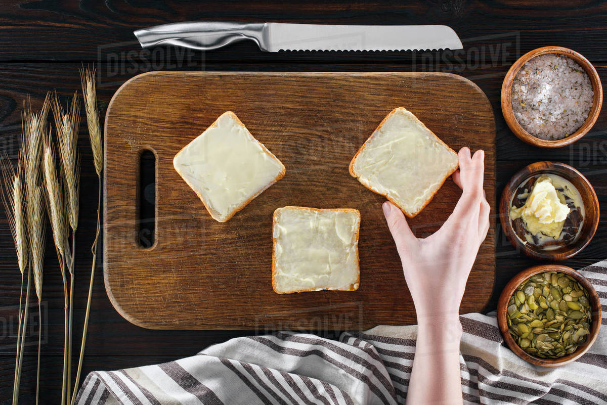 Top view of human hand holding fresh toast with butter from wooden ...