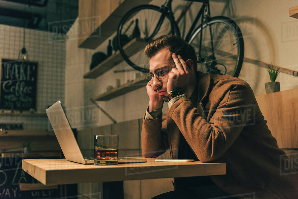 Stressed man looking at laptop screen while working in cafe - Stock ...