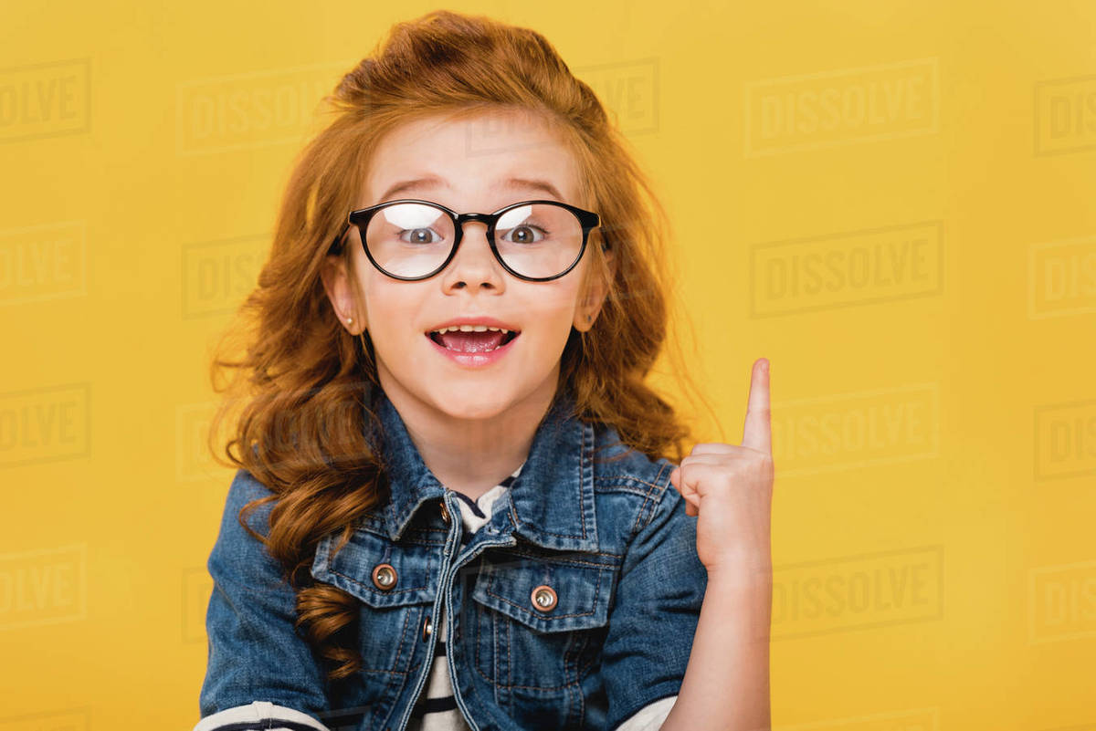 portrait of smiling little kid in eyeglasses pointing up isolated on ...