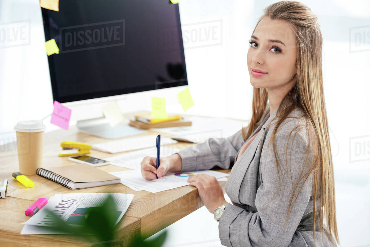 Side view of female marketing manager looking at camera while doing ...