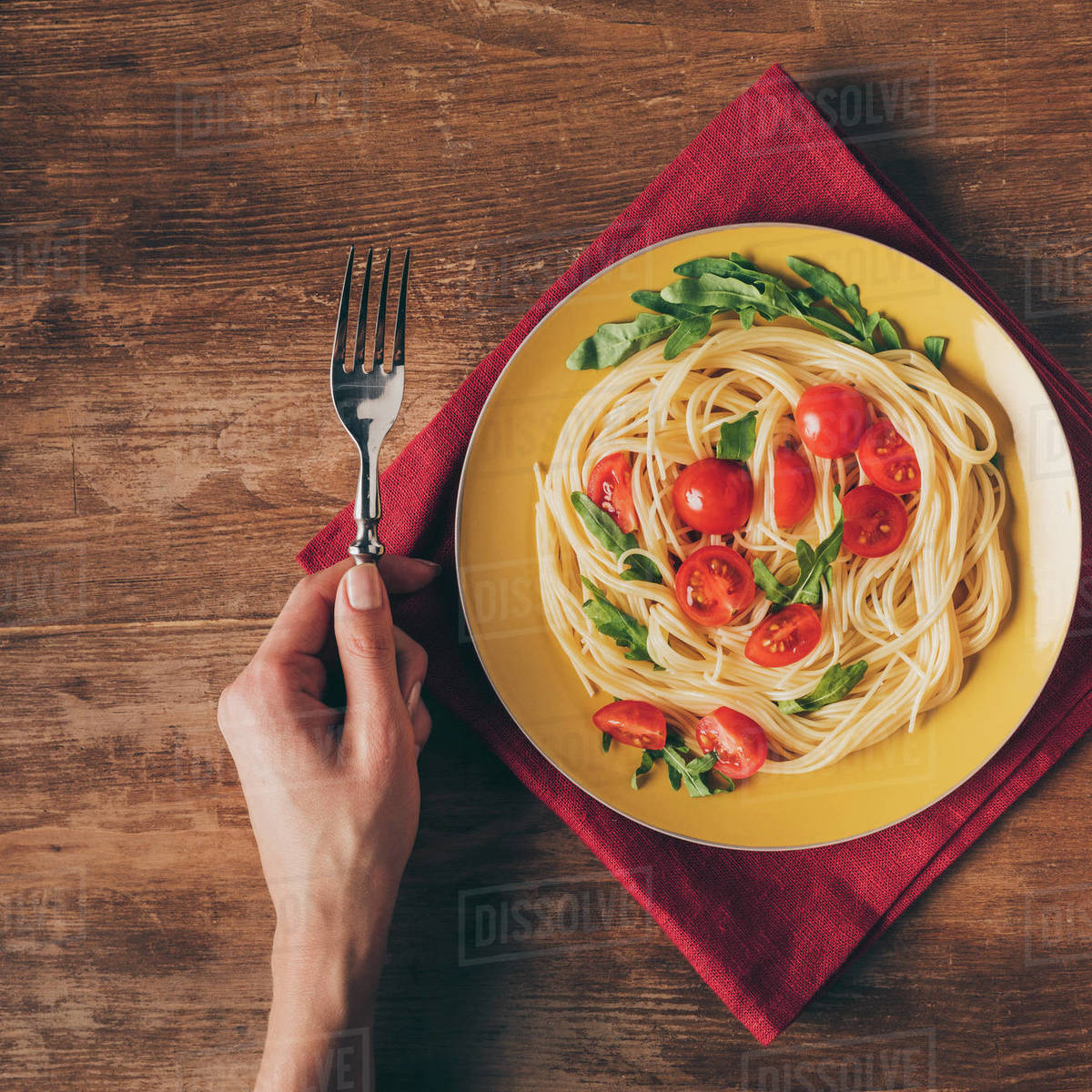 Cropped view of hand with fork at plate with pasta, tomatoes and ...