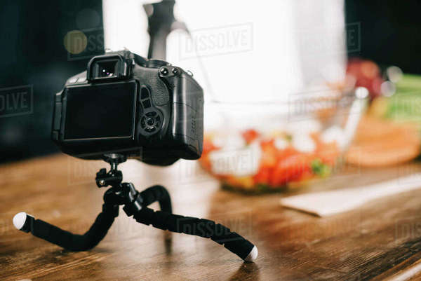 digital camera on table with salad on blurred background - Stock Photo ...