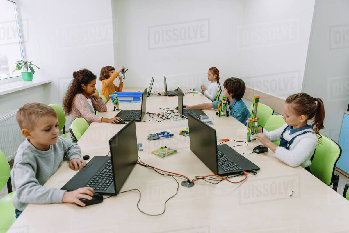 group of focused kids working with computers on machinery class ...