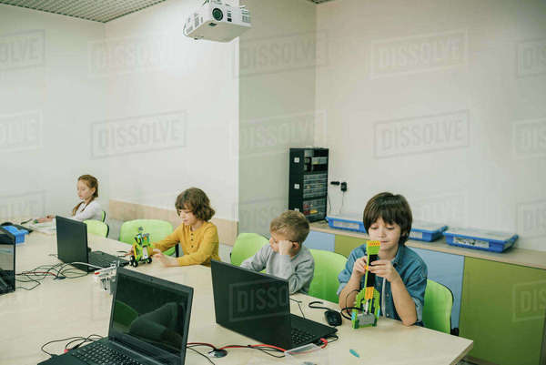 group of focused kids working on projects at stem education class ...