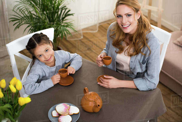 High angle view of happy mother and daughter drinking tea and smiling ...