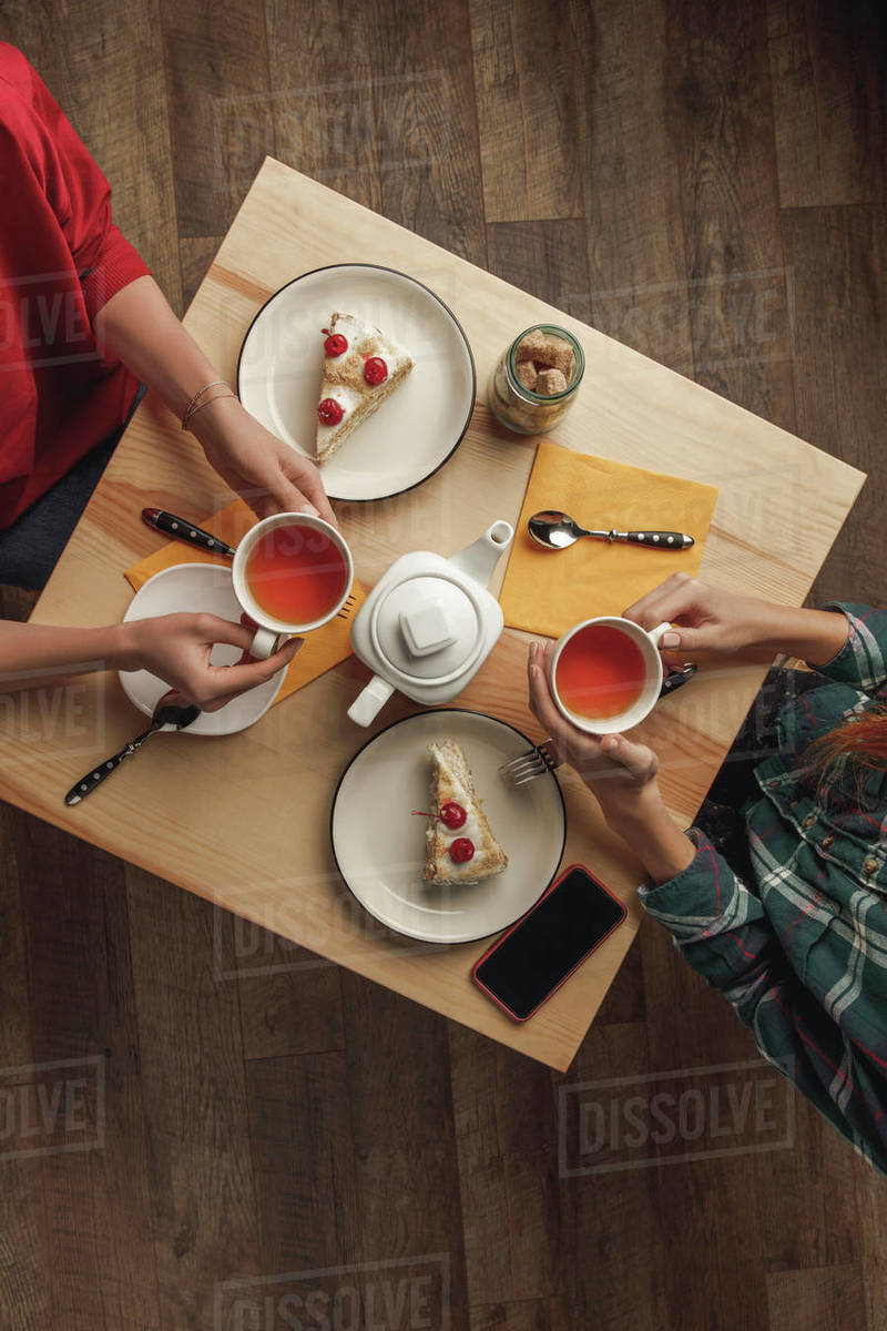 Top view of two people drinking tea above table with pastries and ...