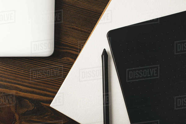 Top view of graphics tablet, laptop and drawing album on wooden table ...