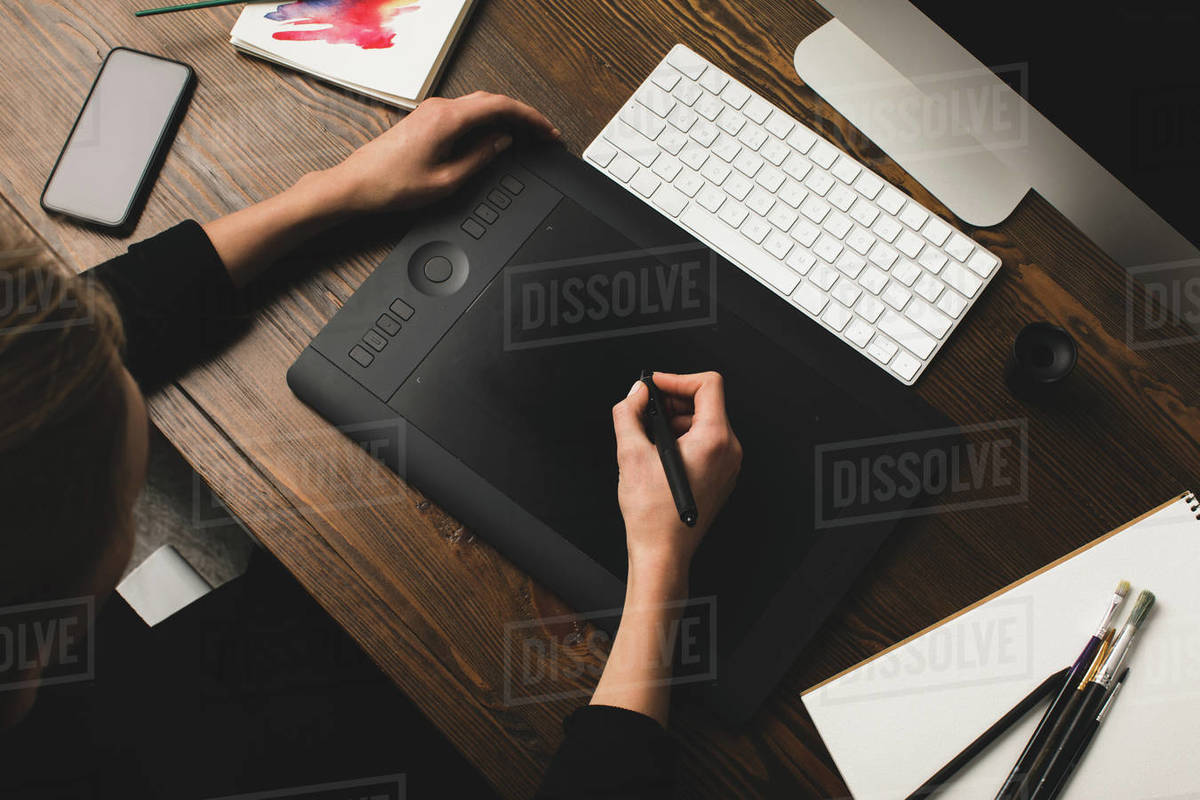 Partial view of designer using graphics tablet at workplace with ...