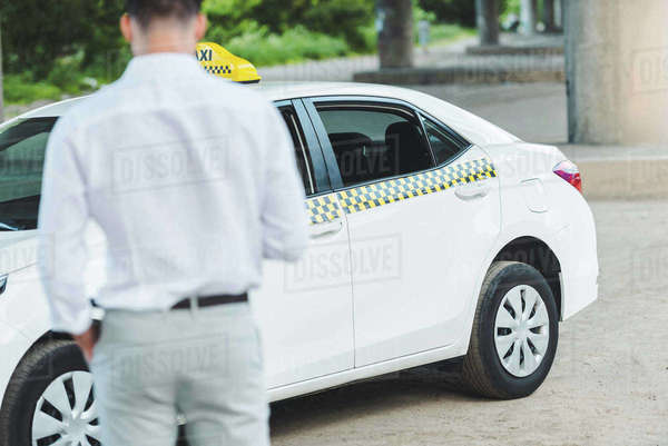 Back view of young male driver going to taxi cab on street - Stock ...