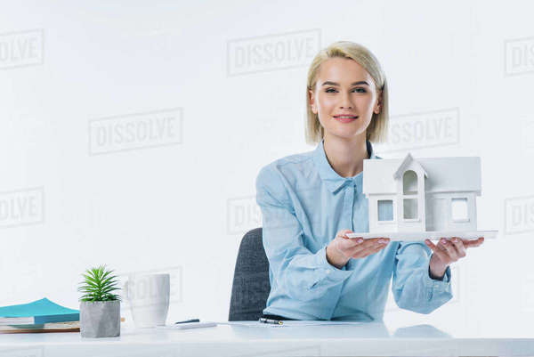 Portrait of real estate agent showing house model at workplace ...
