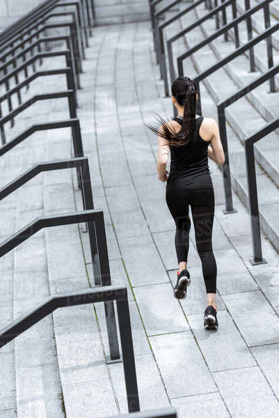 Back view of athletic young woman in sportswear running on stadium ...