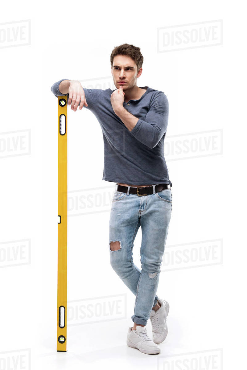 Pensive handsome man holding building level isolated on white, handyman ...