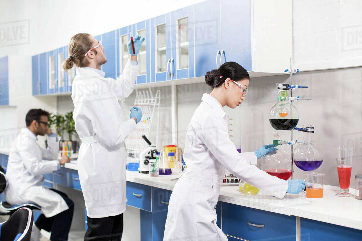 Group of young professional scientists making experiment in research ...