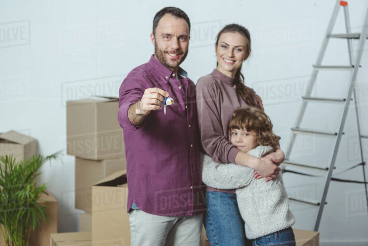 Happy family with one child smiling at camera and holding key from new ...