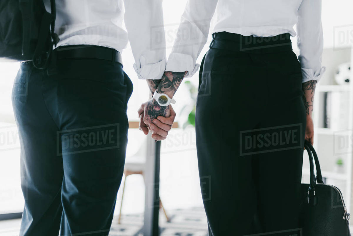 Cropped shot of couple in formal wear holding hands in office - Royalty ...
