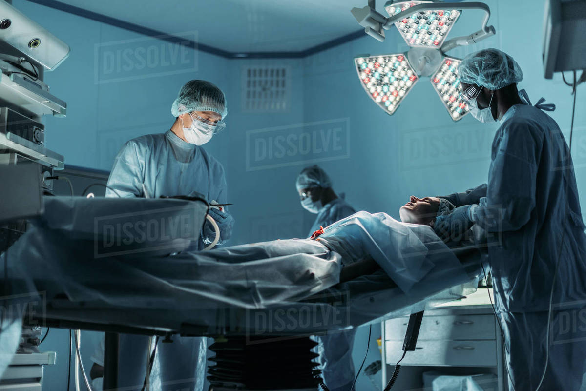 Multicultural doctors preparing patient for surgery in operating room ...