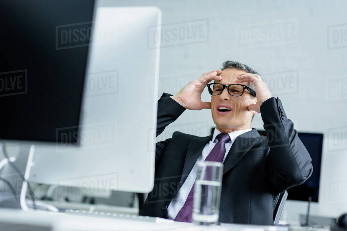 Stressed businessman looking at computer screen at workplace - Stock ...