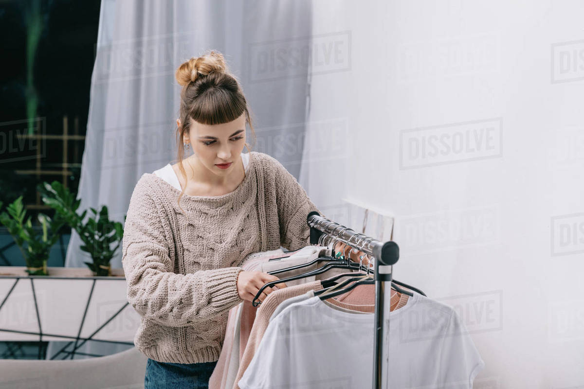 Girl standing at stand with clothes and choosing what to wear - Royalty ...