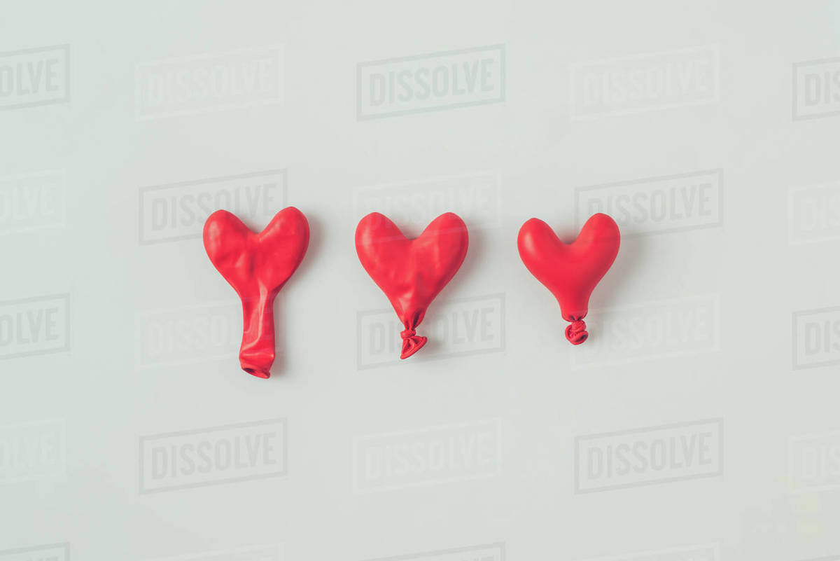 Top view of three deflated heart shaped balloons isolated on white ...