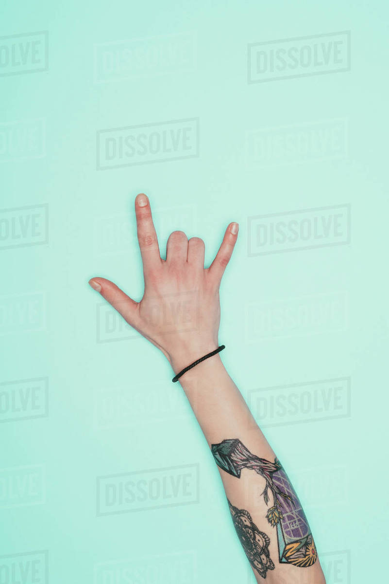 Cropped shot of woman showing horns sign isolated on turquoise ...