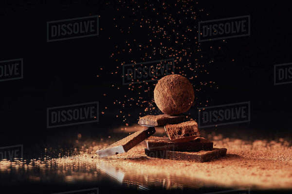 Close up view of truffle on chocolate bars with cocoa powder on black ...