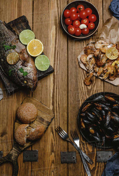 Top view of assorted seafood and baked fish with bread and tomatoes on ...