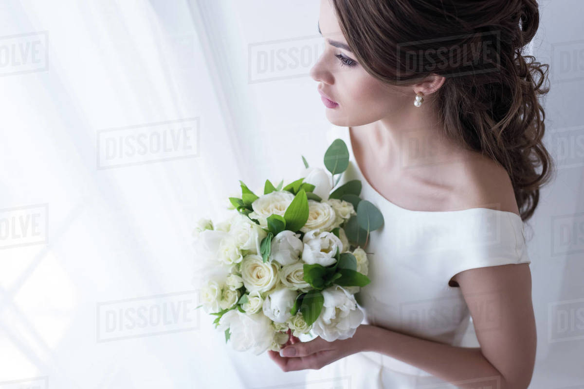 Attractive bride in traditional dress holding wedding bouquet - Royalty ...