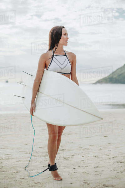 Attractive young woman in swimsuit holding surfboard and walking on ...