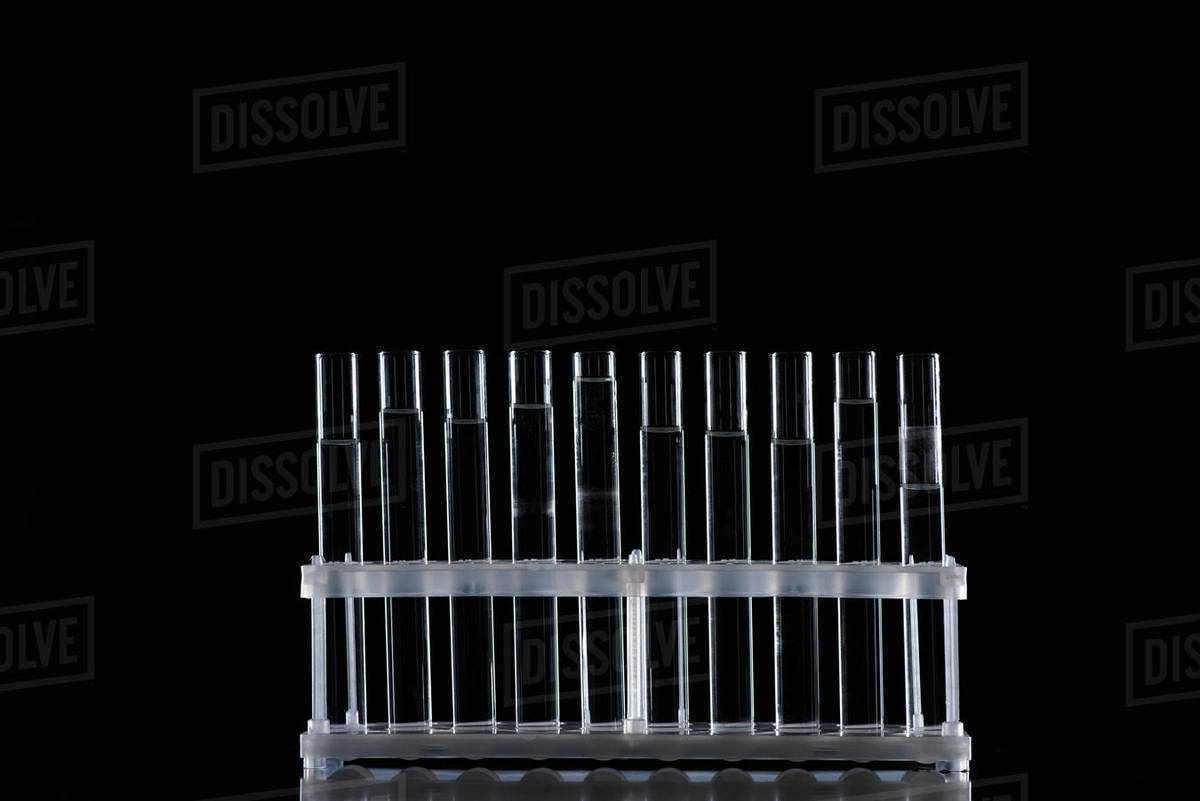 Row of glass tubes with liquid on stand isolated on black - Royalty ...