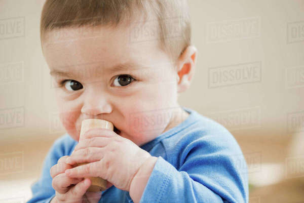 Portrait of adorable child looking at camera with wooden toy in hands ...