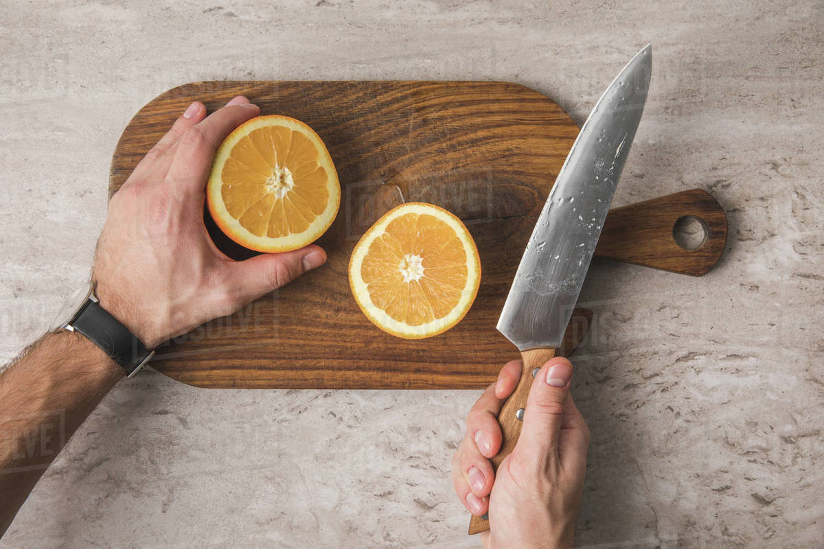 Cropped image of man cutting orange - Royalty-free Stock Photo | Dissolve