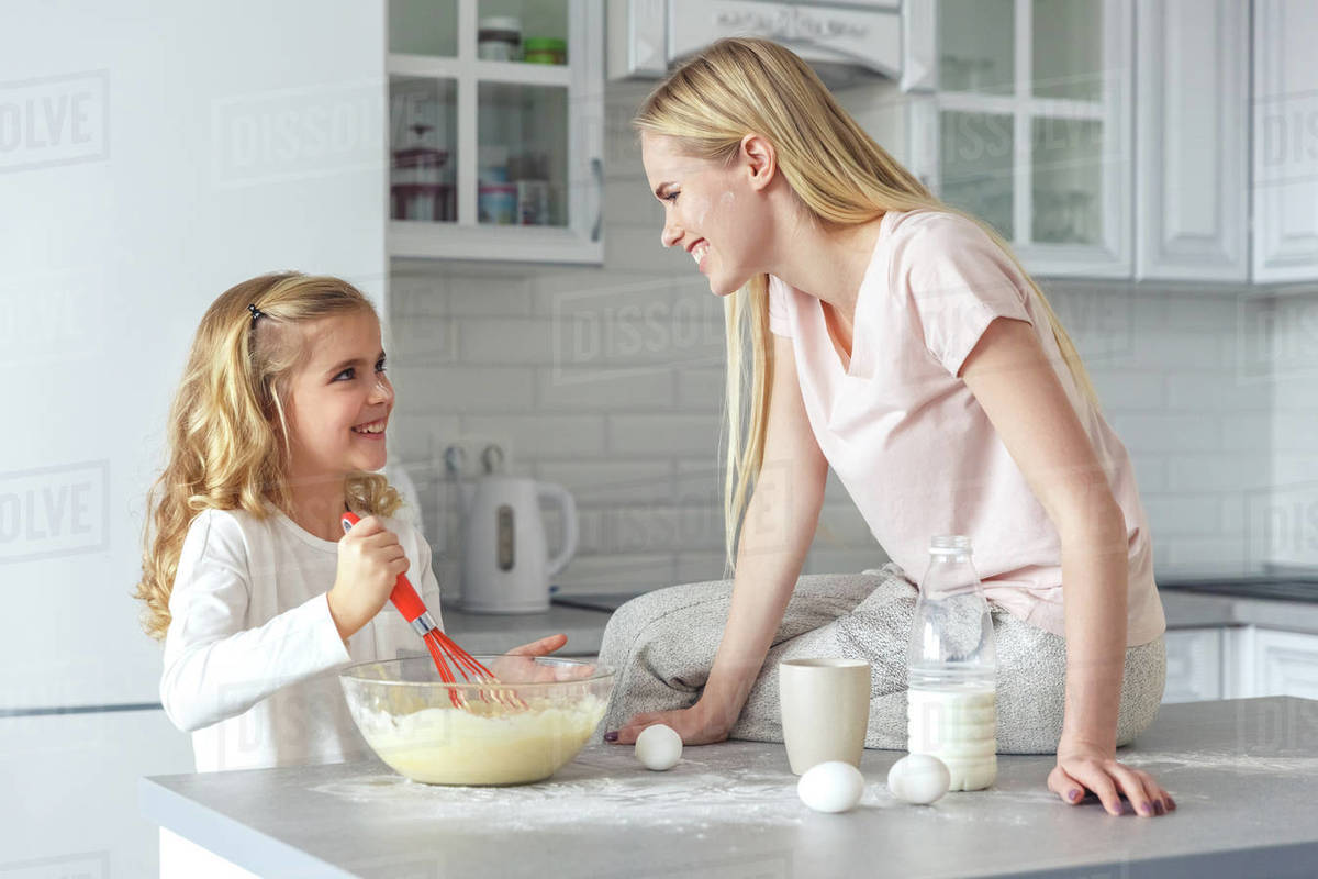 Adorable young daughter helping mother to cook breakfast - Royalty-free ...