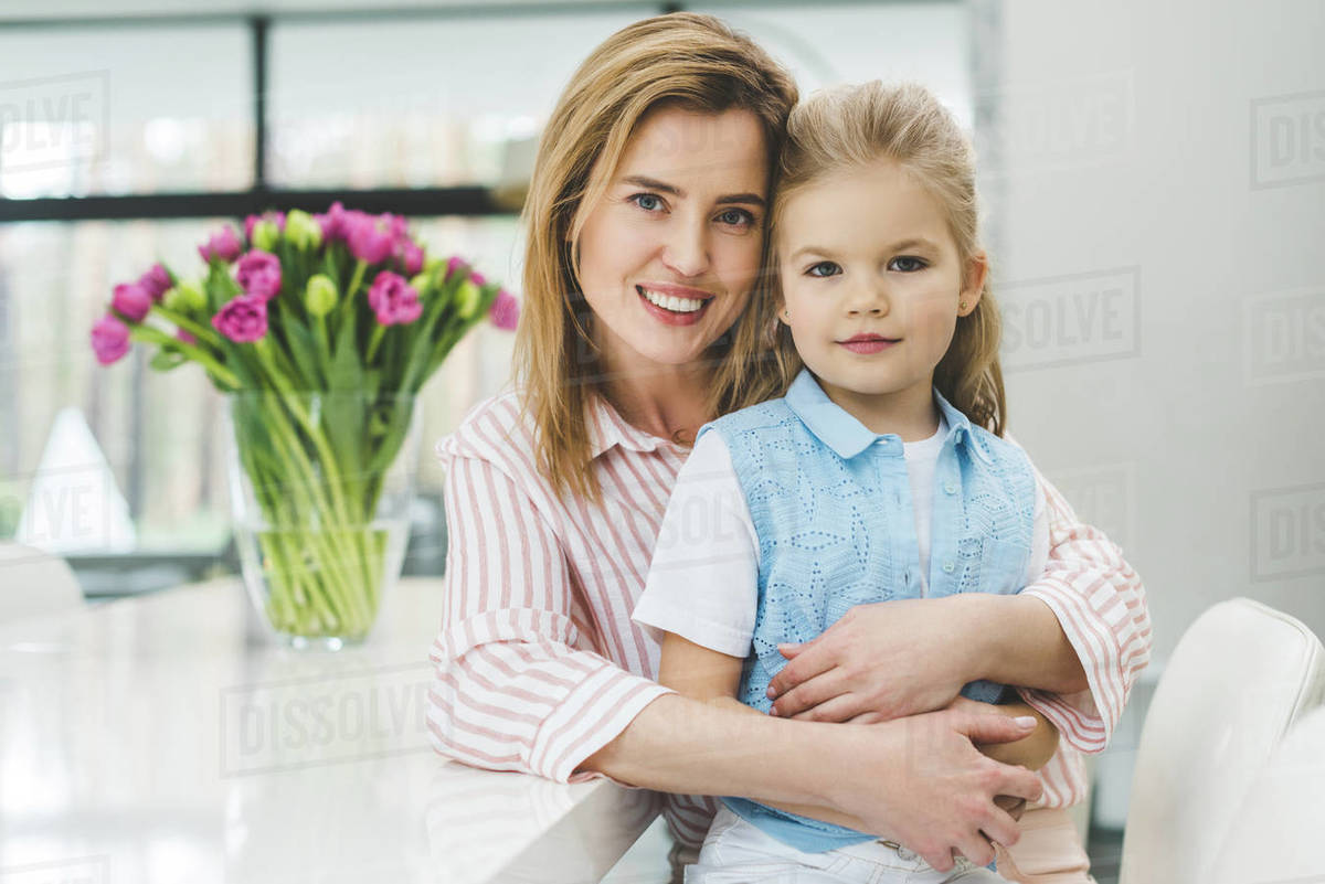 Portrait of smiling mother hugging little daughter at home - Royalty-free Stock Photo | Dissolve