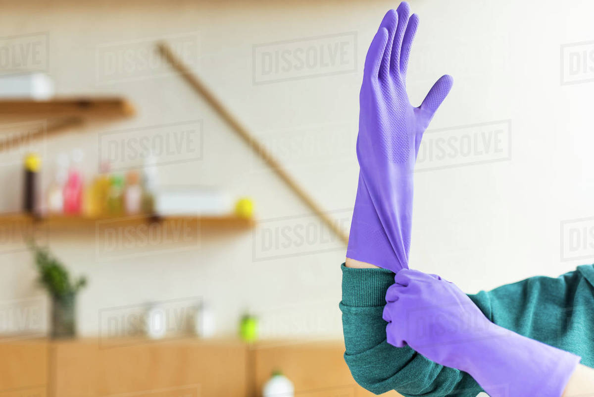 Cropped shot of young woman wearing rubber gloves while cleaning house ...