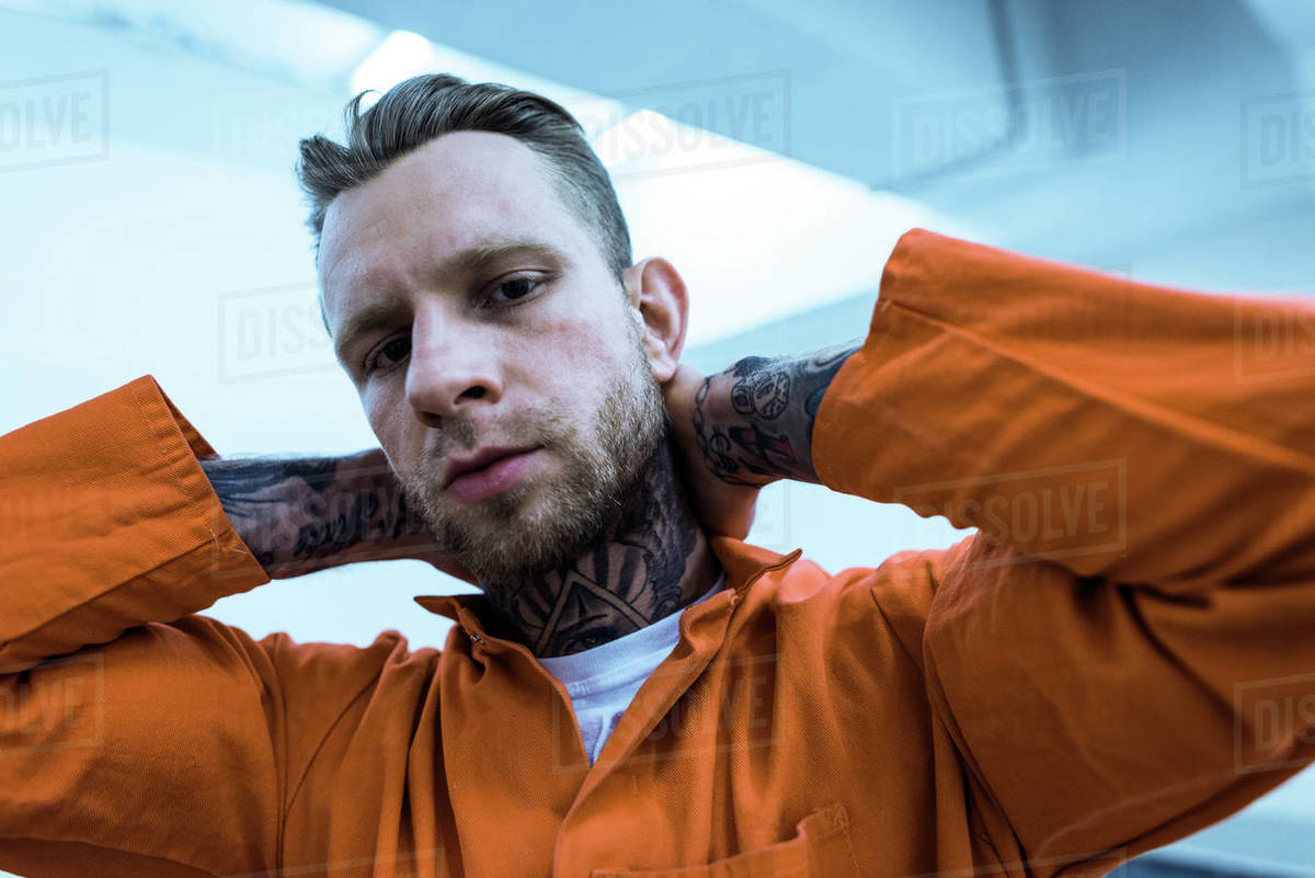 Tattooed prisoner with hands behind head looking at camera - Royalty ...